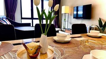 Uma mesa de jantar com um vaso de flores brancas, uma travessa de comida e uma bandeja com pratos e xícaras.