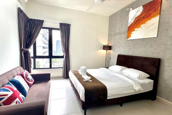 Quarto de hotel com cama, sofá, janela com cortinas e um quadro na parede.