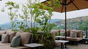 Terraço no telhado com um sofá, uma mesinha e um vaso de planta.