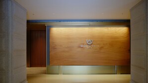 Uma área de recepção com painel de madeira e um logotipo, piso lustroso e vista para o mar.