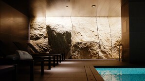 Uma área de spa com parede de pedra, piscina e assentos.