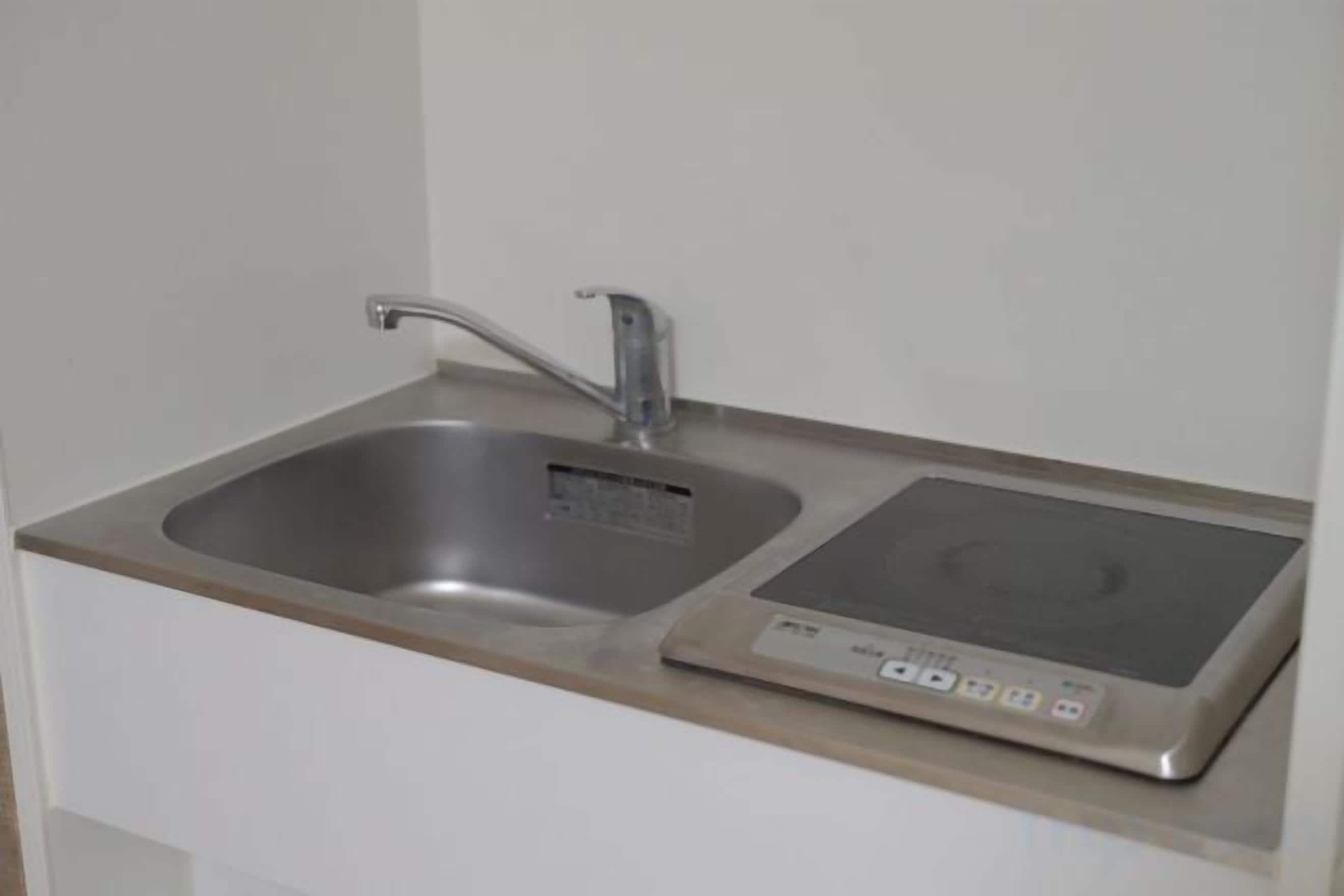 Cozinha com pia de aço inoxidável e fogão por indução embutido.