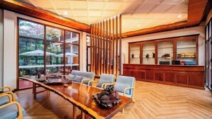 Uma sala de conferências ampla com uma longa mesa de madeira, várias cadeiras e um arranjo decorativo.