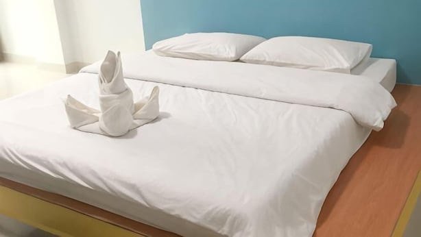 Uma cama com lençóis brancos e uma escultura de toalha sobre o lençol.