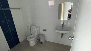 Um banheiro com vaso sanitário, lixeira, pia e espelho.