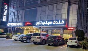 Exterior do Hotel City Tower, com vários carros estacionados na frente.