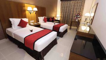 Quarto de hotel com duas camas, uma mesinha, um espelho e uma cortina.