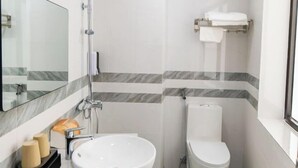 Uma casa de banho moderna com cabine de duche em vidro, uma sanita e uma pia branca.