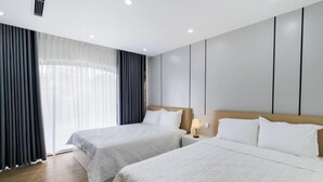 Quarto de hotel com duas camas, uma janela grande com cortinas e design moderno.