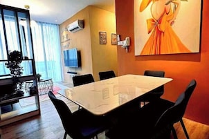 Uma sala de conferências com uma mesa de mármore, cadeiras pretas, uma televisão e um quadro na parede.