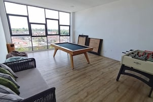 Um quarto com mesa de pebolim, mesa de bilhar e um sofá.