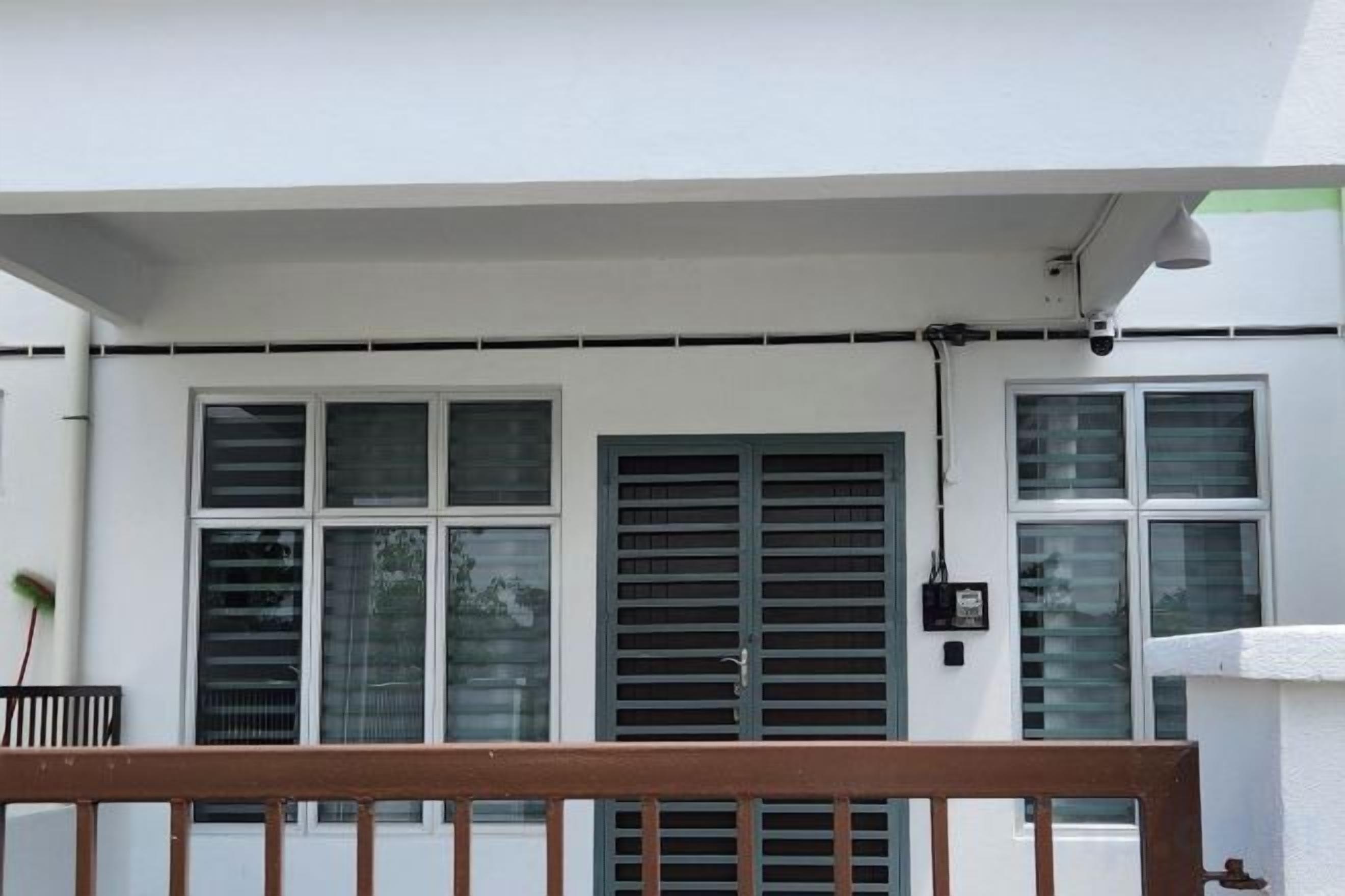 Um edifício branco com varanda, janelas amplas e uma câmera de segurança.