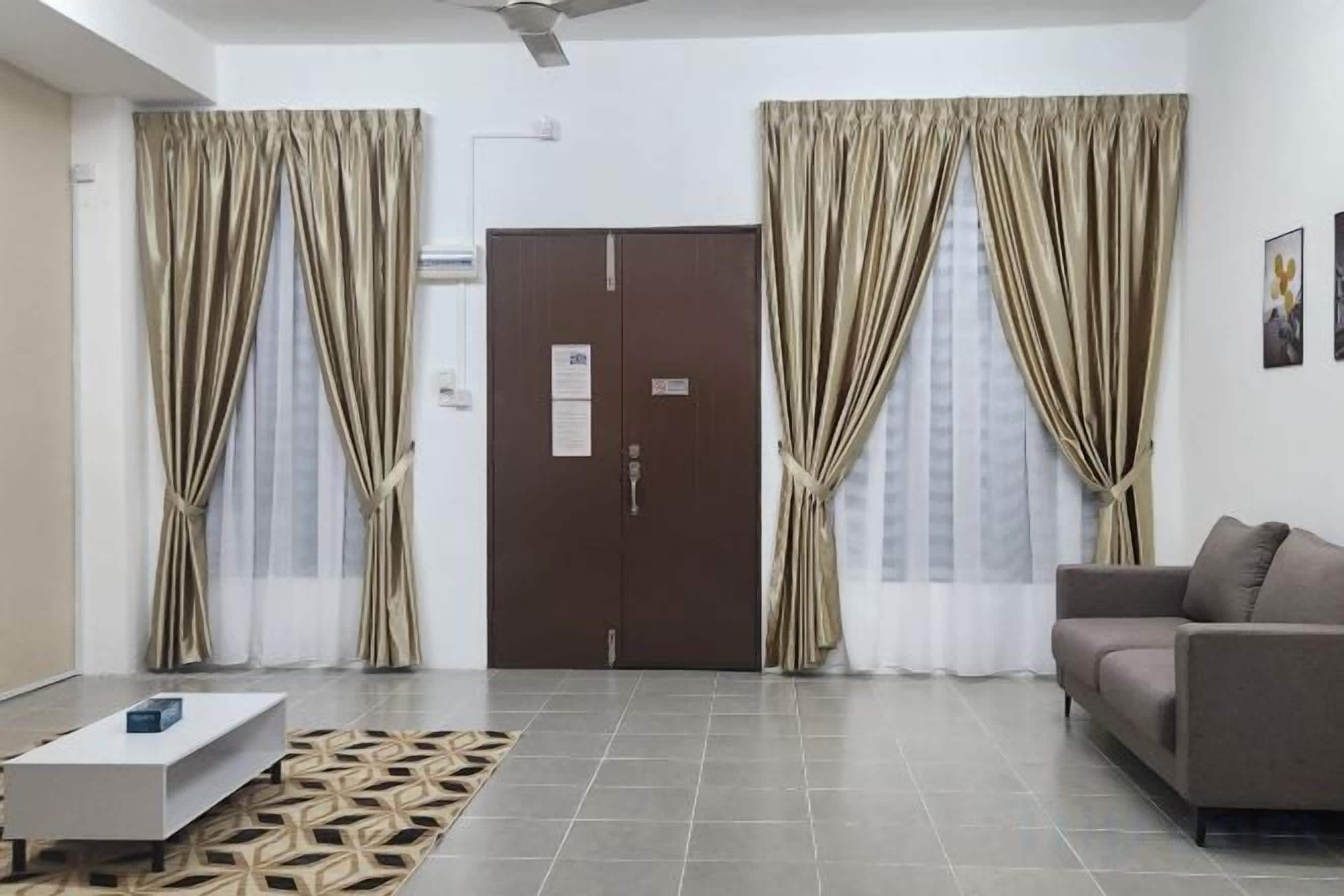 Quarto com sofá, mesa de centro, cortinas, porta e tapete estampado.