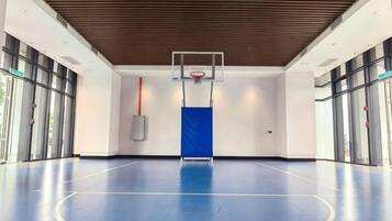 Uma quadra de basquete interna com piso azul, um aro de basquete e teto de madeira.