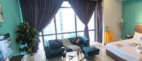 Quarto de hotel moderno com uma cama grande, um sofá, uma mesa de centro e uma televisão.