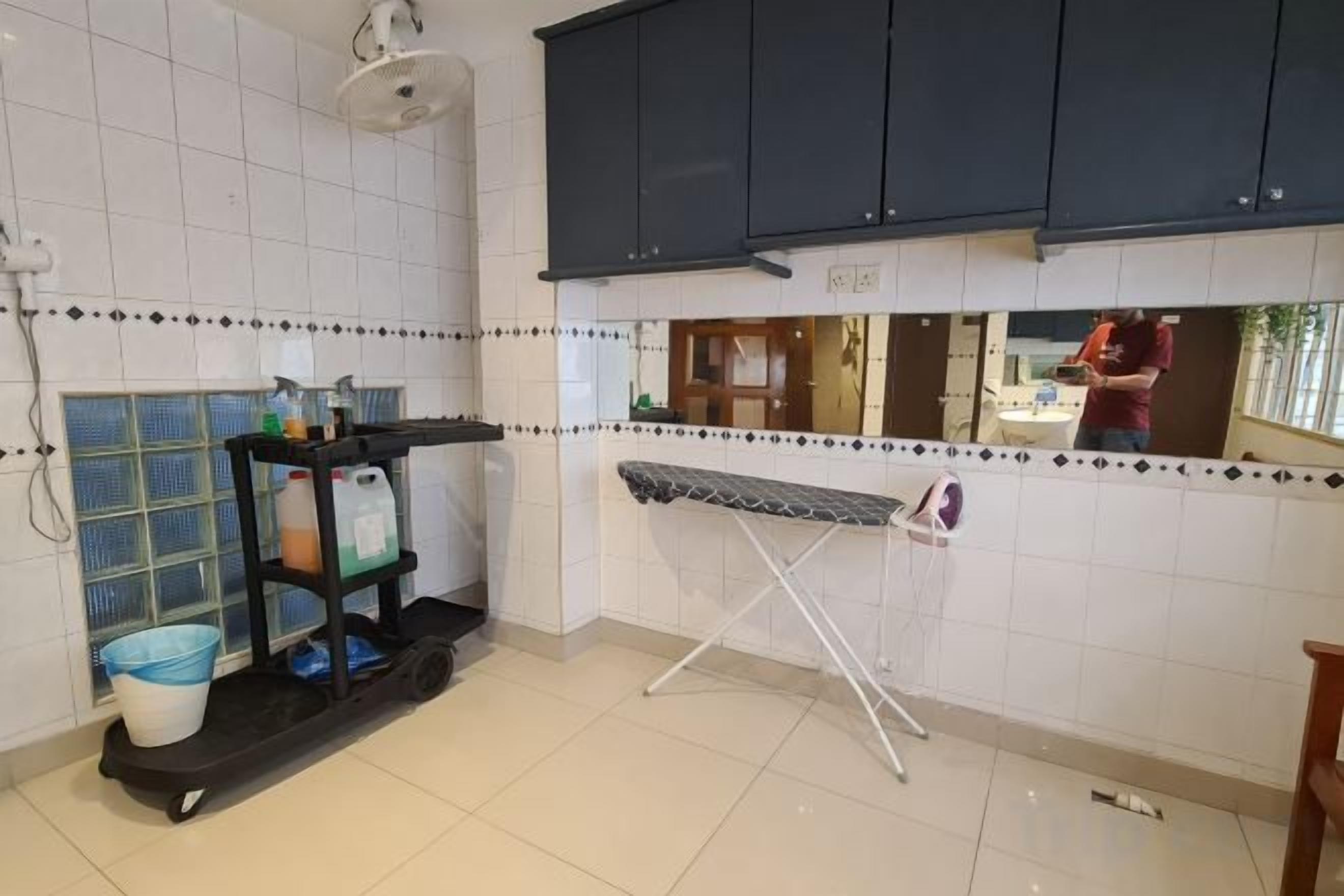 Cozinha com paredes de azulejos brancos, bancada preta e um escorredor.