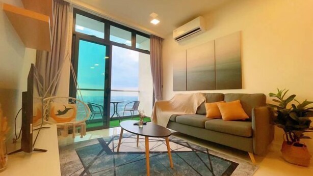 Uma sala de estar moderna com um sofá, uma mesa de centro e uma televisão. Há uma varanda com vista.