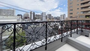 Varanda com grades de ferro forjado com vista para um horizonte urbano com vários edifícios.