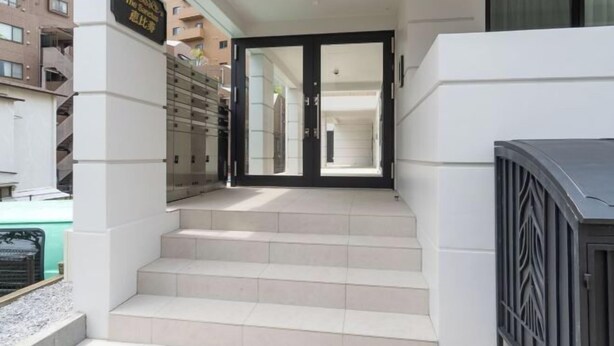 Entrada de um edifício moderno, com escadas que levam a uma porta de vidro.