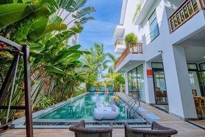 Piscina interna com um flutuador de cisne, cercada por vegetação exuberante e arquitetura moderna.