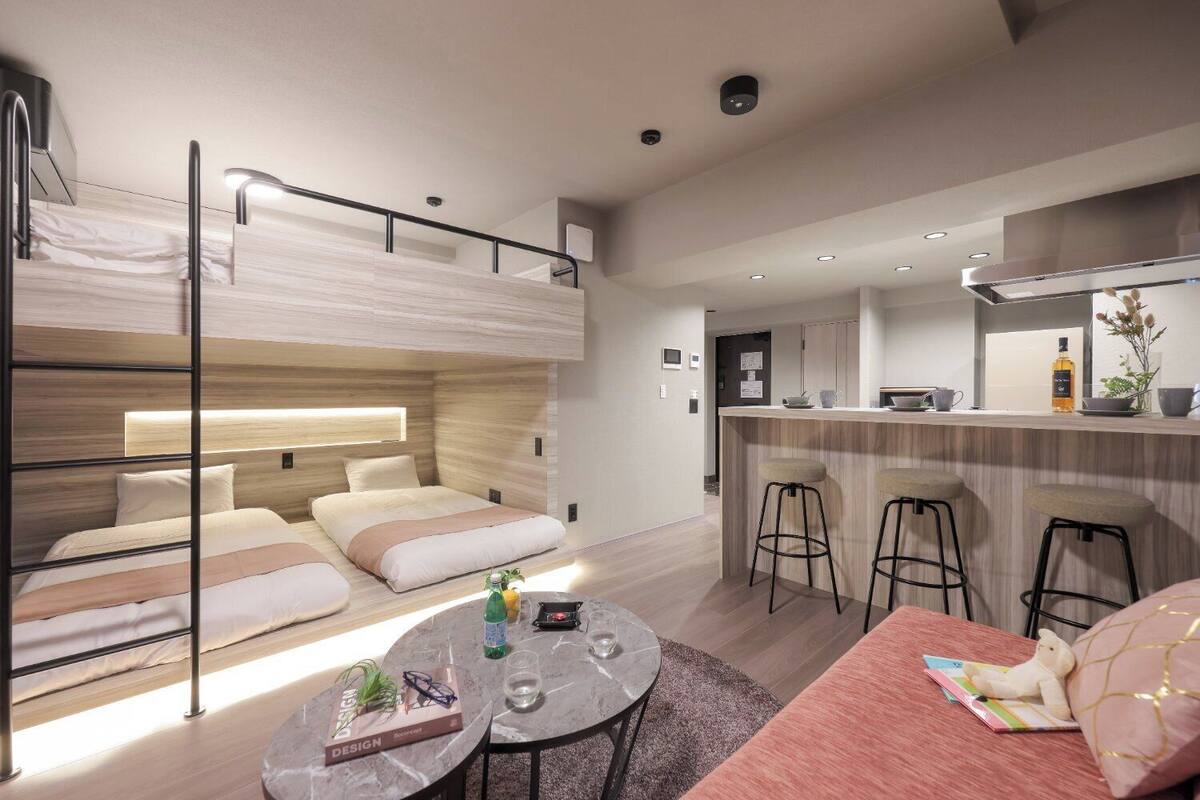 Um espaço de estar moderno e compacto com beliche, cozinha e um pequeno espaço para sentar.