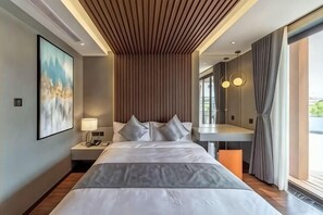 Quarto de hotel moderno com cama grande, mesa de cabeceira, luminária e janela ampla com cortinas.