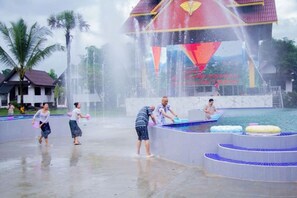 Uma área de recreação com água, com vários jatos e uma piscina.