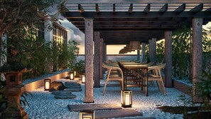 Uma área de estar tranquila ao ar livre, com um pérgola de madeira, lanternas de pedra e uma fileira de cadeiras de madeira.