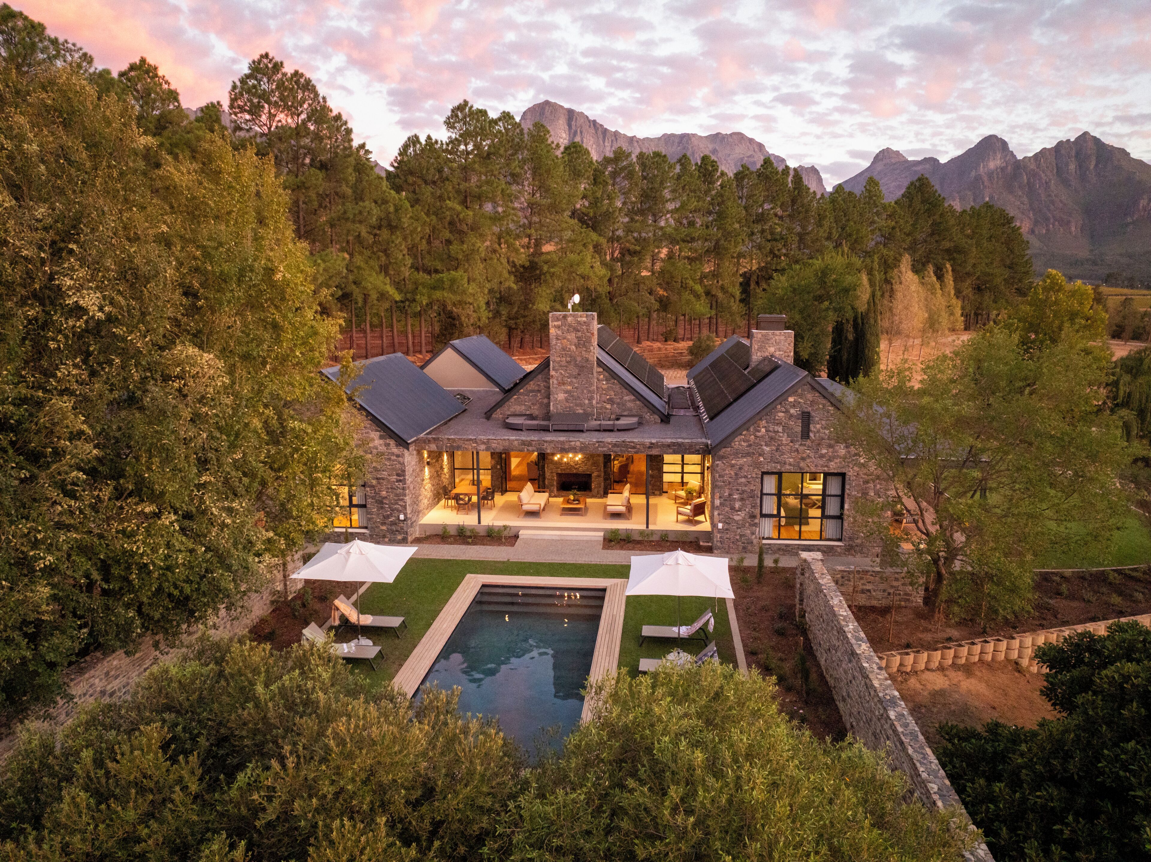 Uma casa moderna com piscina, cercada por árvores e montanhas.
