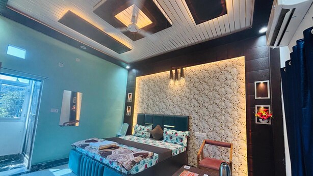 Quarto moderno com uma cama grande, uma mesinha e um detalhe decorativo na parede.