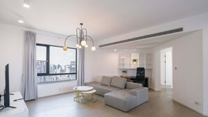 Uma sala de estar moderna com sofá, banquinho e mesa de jantar.