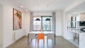 Uma cozinha moderna com bancada branca, micro-ondas preto e janela com vista para a cidade.