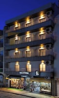 Um edifício com vários andares, varandas e lojas no térreo.