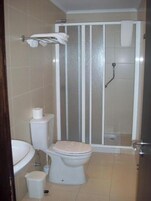 Uma casa de banho com sanita, lavatório e cabine de duche.
