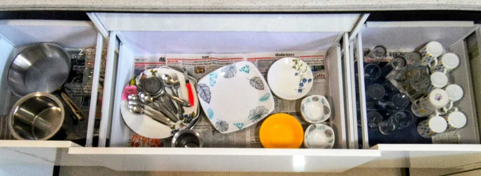 Uma gaveta com diversos utensílios de cozinha, pratos e tigelas.