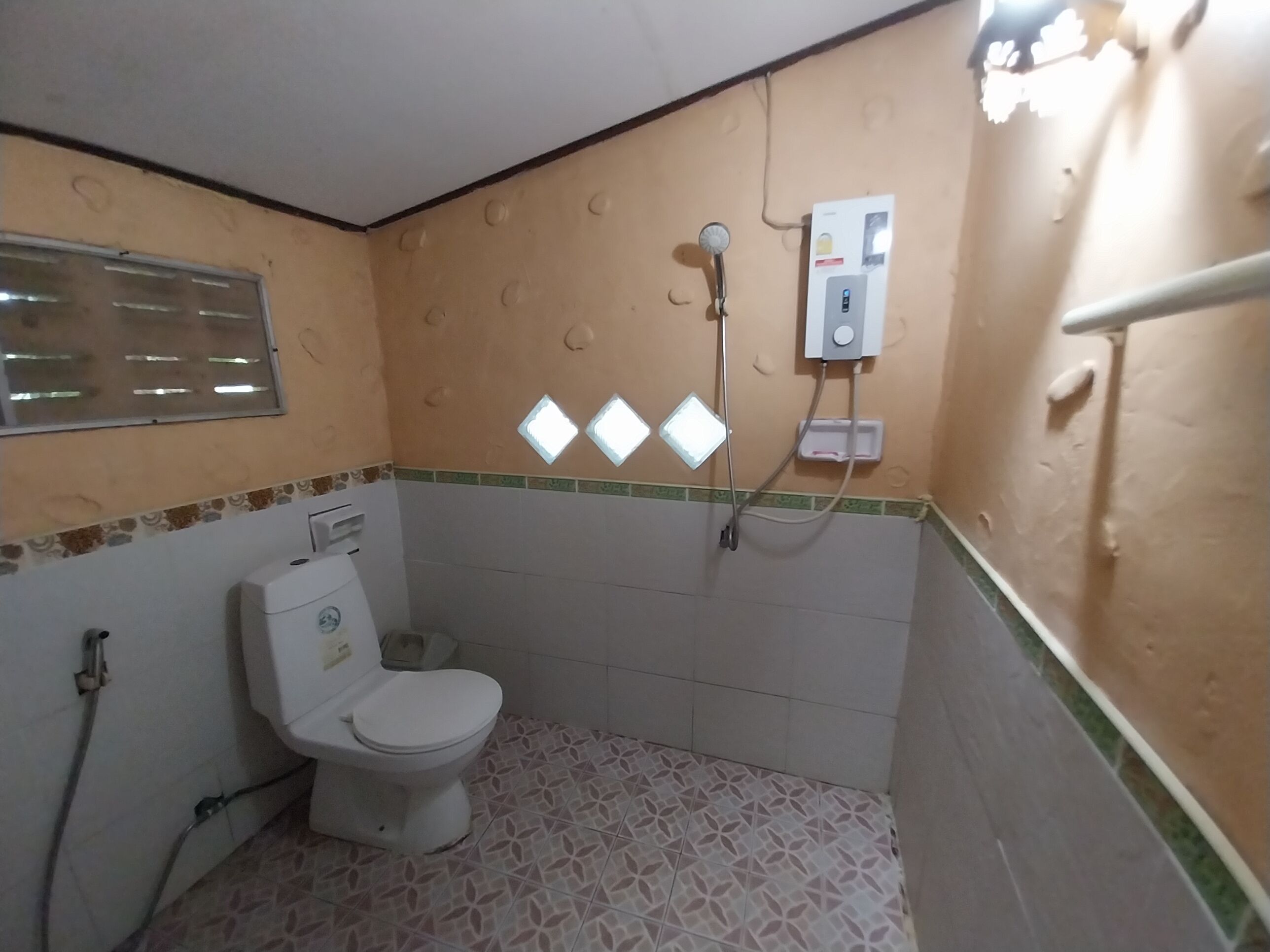 Um banheiro pequeno com vaso sanitário, chuveiro e aquecedor na parede.