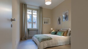 Quarto com cama, radiador, janela com cortinas e obras de arte nas paredes.