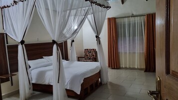 Quarto com cama sob dossel, uma cadeira e uma janela com cortinas.