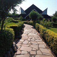Uma trilha de pedras que leva a um edifício moderno com telhado triangular.