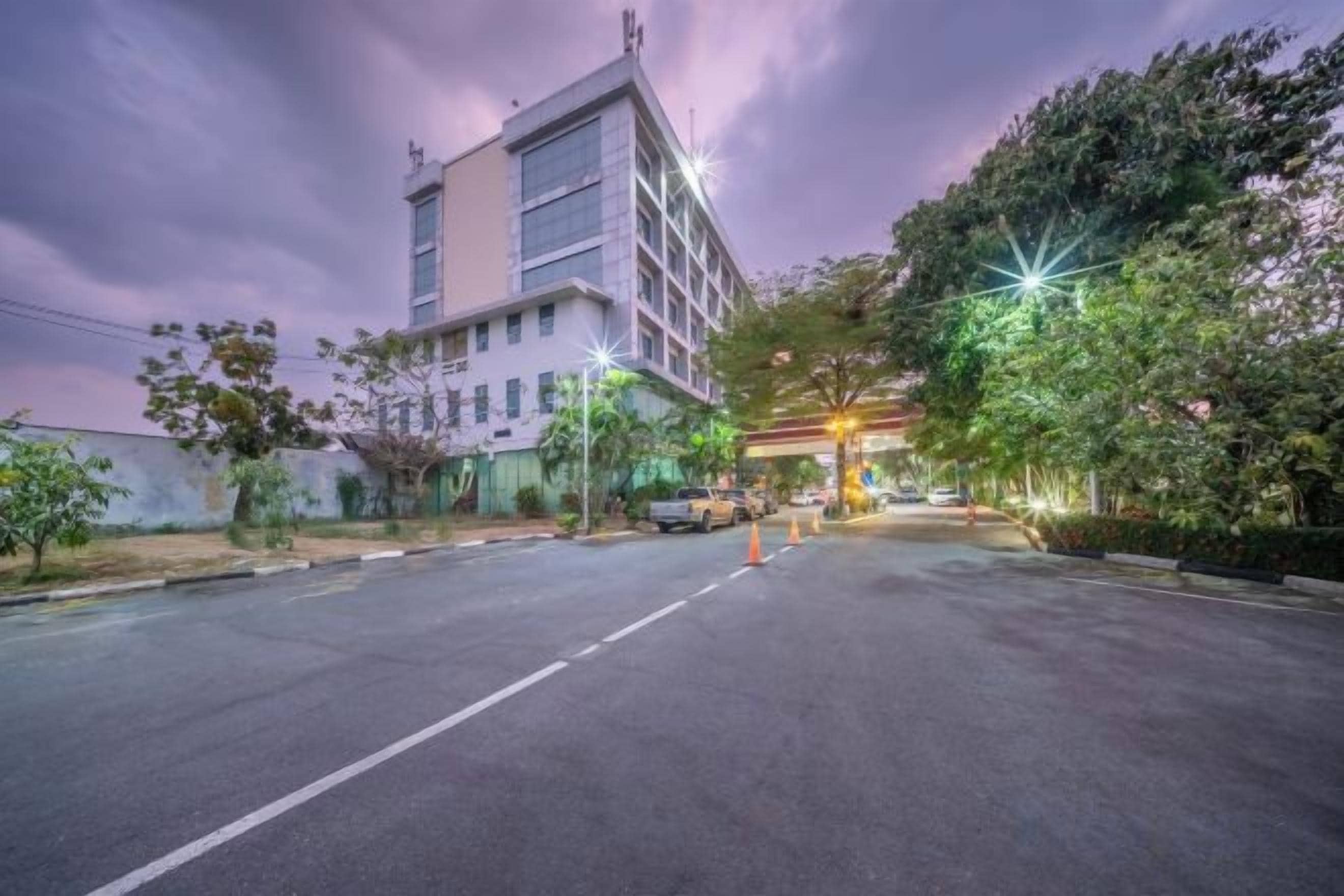Um edifício com vários andares, um estacionamento e árvores.