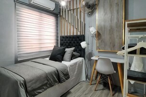 Quarto compacto com cama, mesa de cabeceira e guarda-roupa.
