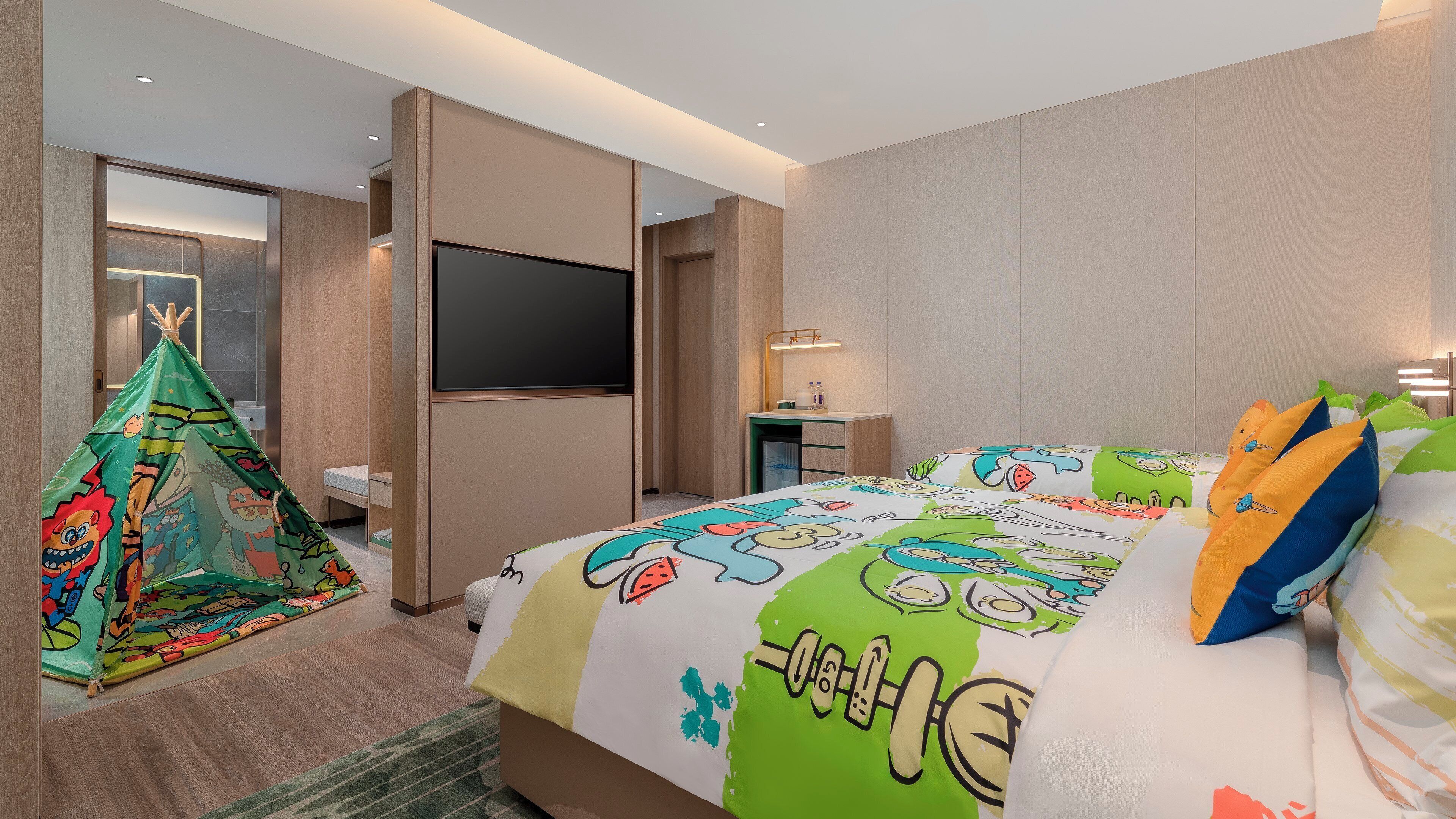 Quarto de hotel com cama, televisão, escrivaninha e uma estrutura semelhante a uma tenda.