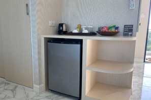 Uma cozinha compacta equipada com geladeira embutida, cafeteira e um pequeno armário com diversos objetos.