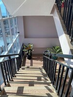Uma escadaria com grades de metal, plantas em vasos e vista para o exterior.