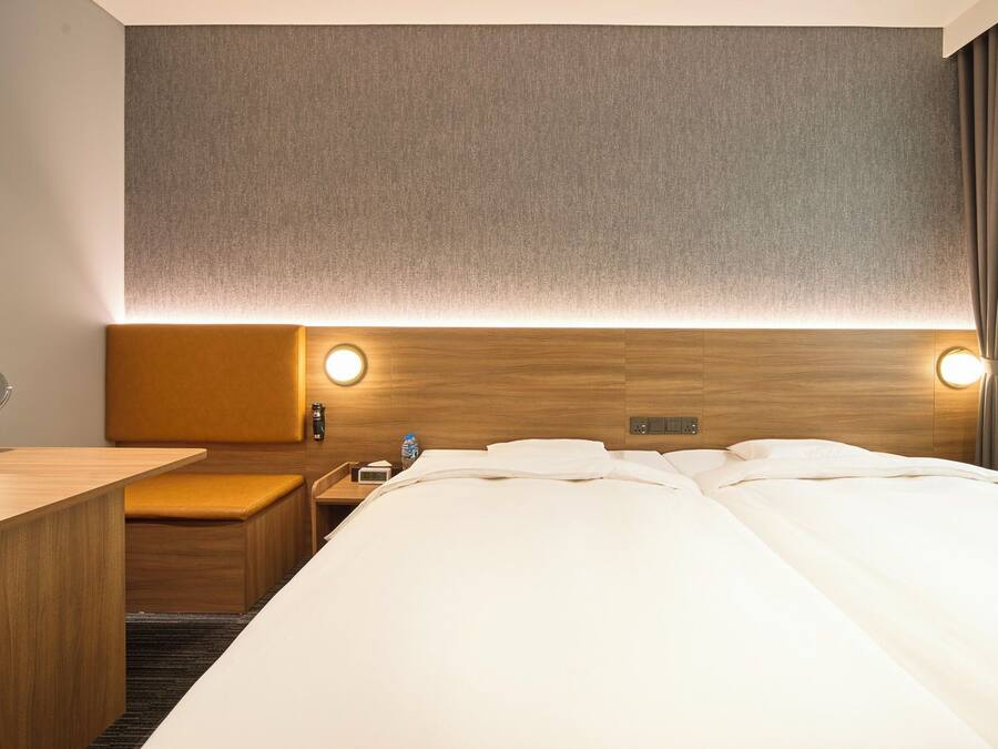 Quarto de hotel com uma cama, mesa de cabeceira e um espelho.