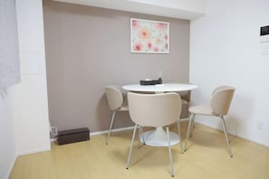 Quarto pequeno e moderno com uma mesa redonda e quatro cadeiras, uma obra de arte na parede e uma tomada no chão.