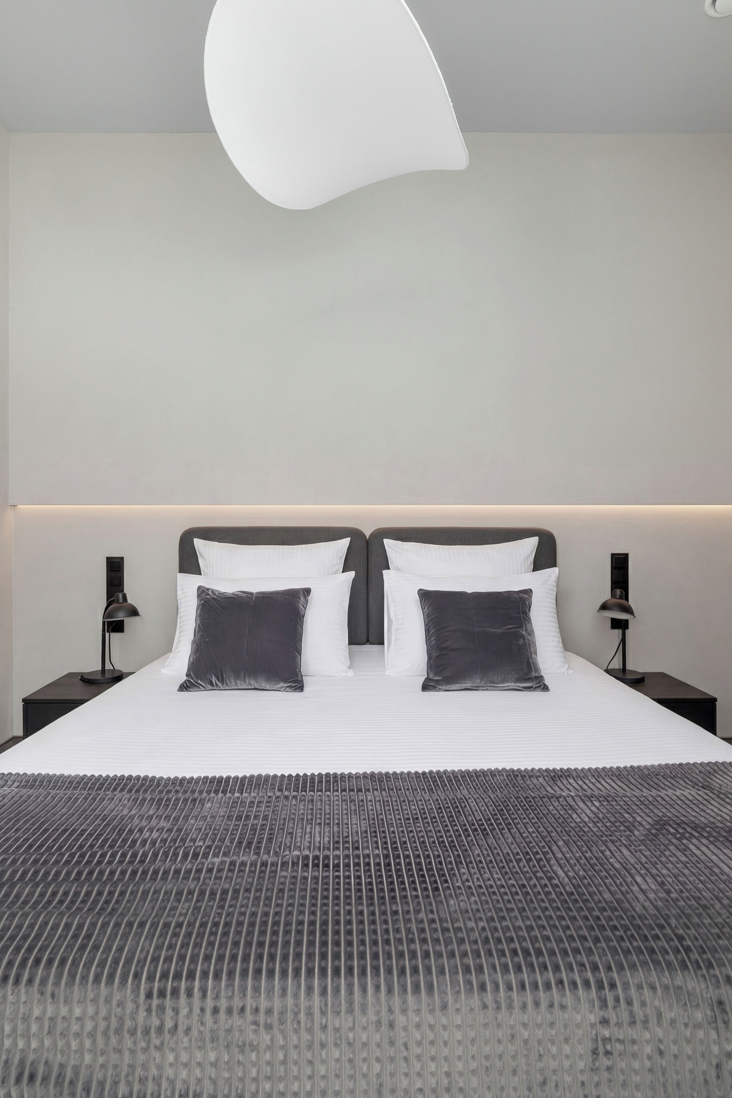 Quarto moderno com cama grande, duas mesas de cabeceira e um lustre de design exclusivo.