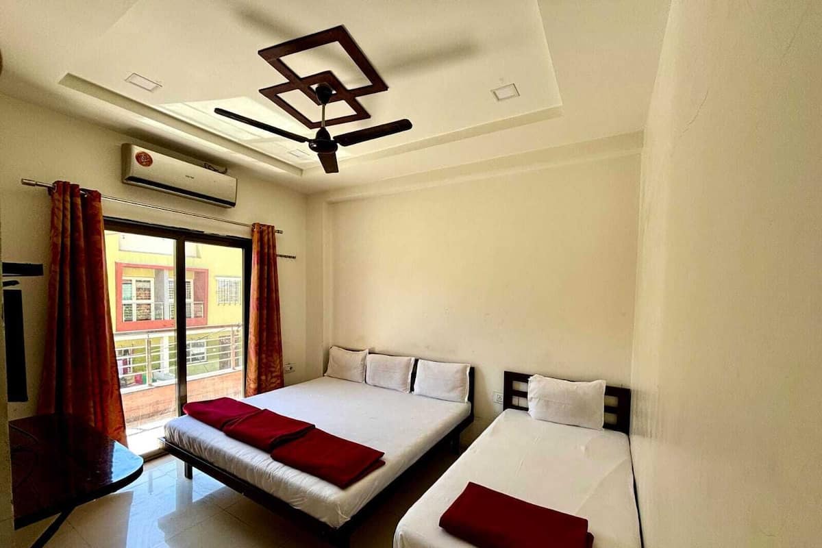 Quarto de hotel com duas camas, ventoinha no teto, ar condicionado e vista para a varanda.