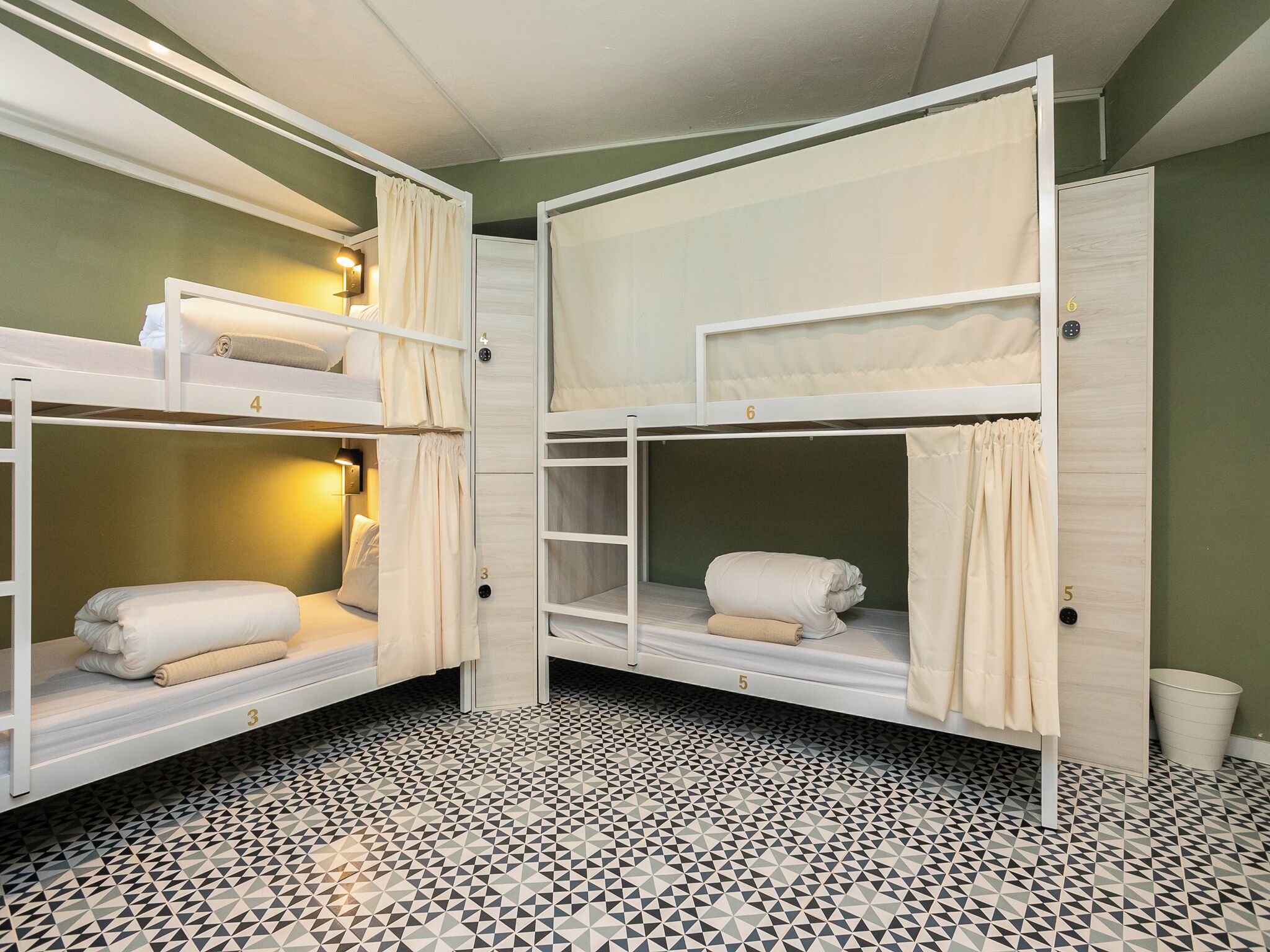 Quarto com beliches, portas numeradas e piso estampado.