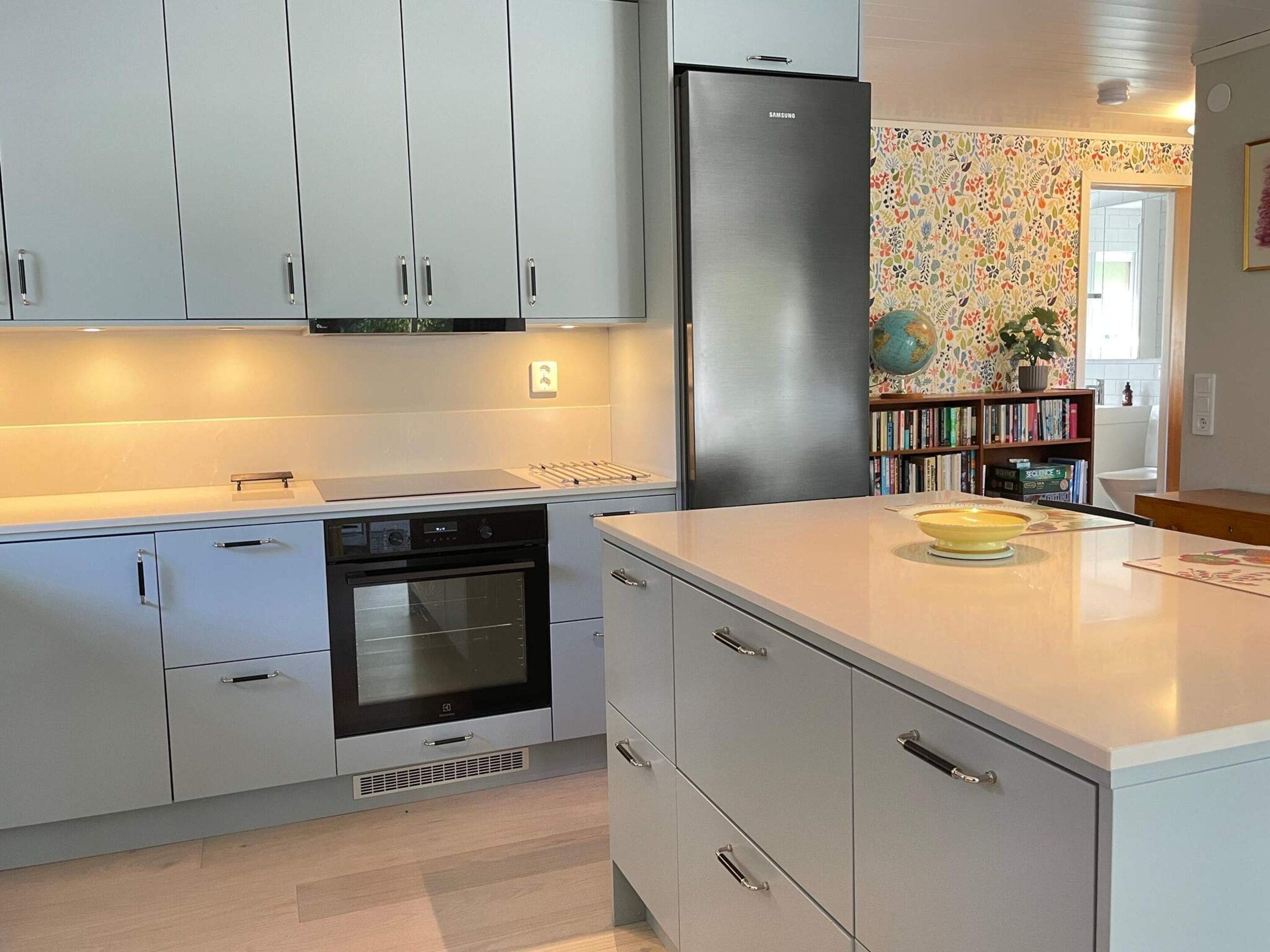 Cozinha moderna com eletrodomésticos de aço inoxidável, armários em tons claros e uma ilha central.